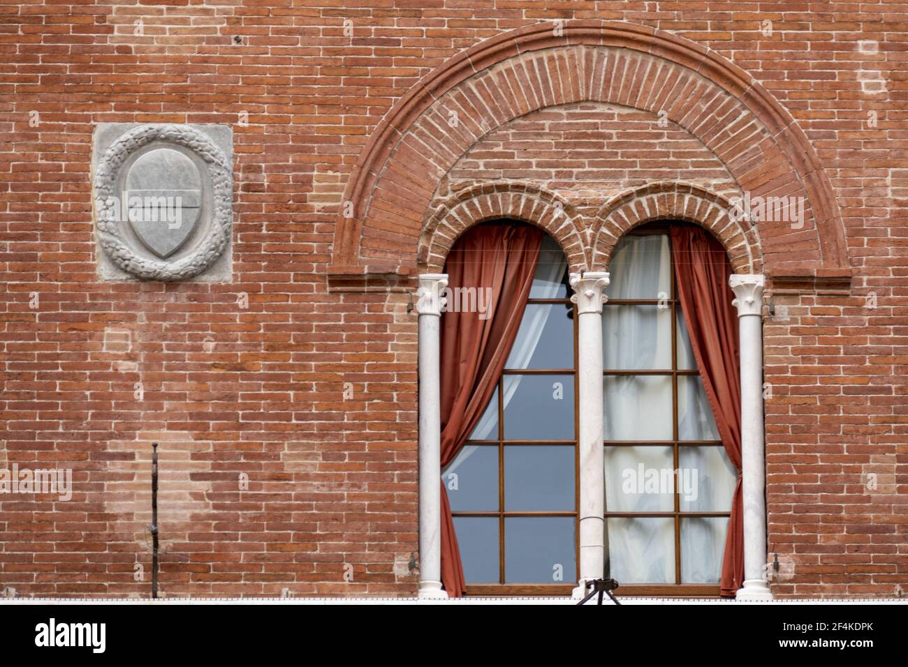 Brick arched windows with white columns and red curtains in Pisa ...