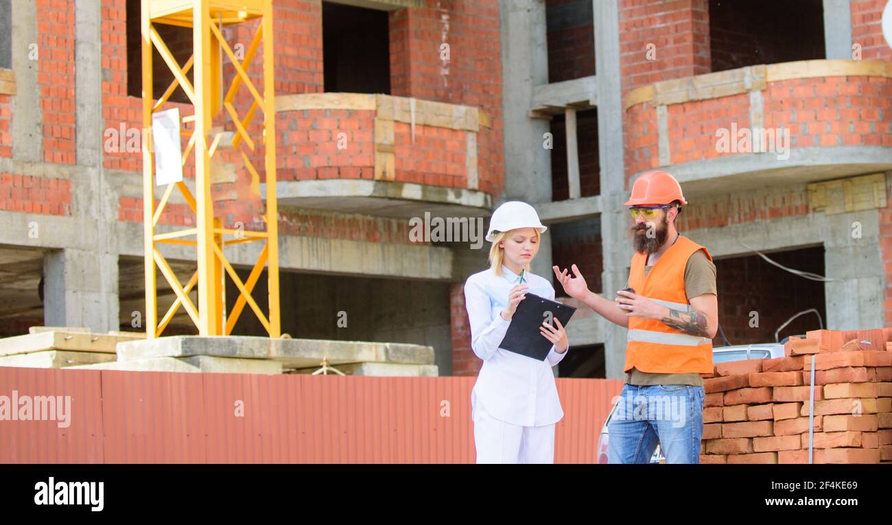 Woman engineer and builder communicate at construction site ...