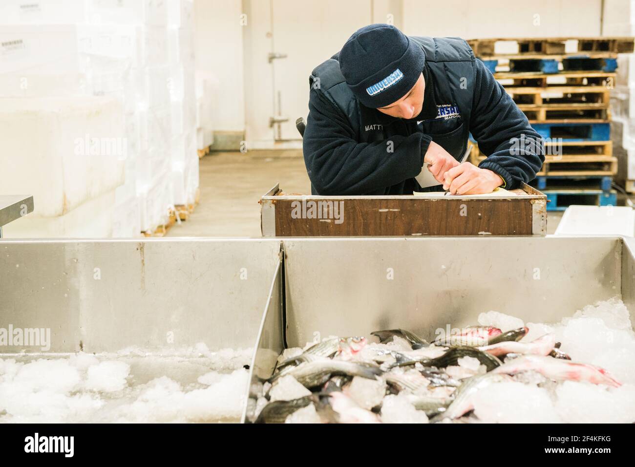 New York City, USA. Wholesale market stall employee crunching numbers ...