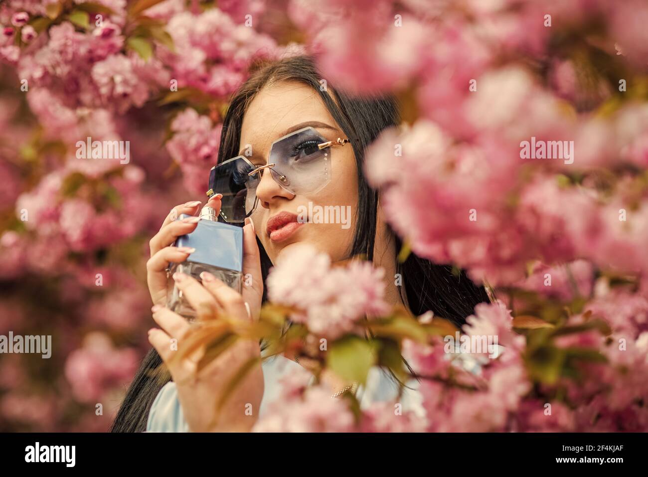Luxury fragrance. Fashionable woman hold perfume bottle. Cherry blossom ...