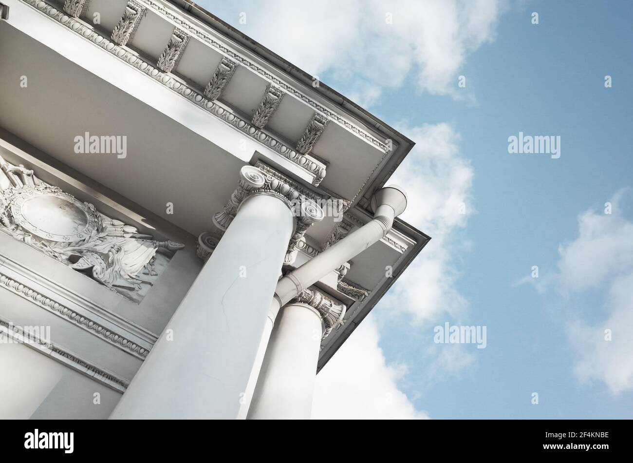 Corner with white pillars of classical portico under cloudy sky on a ...