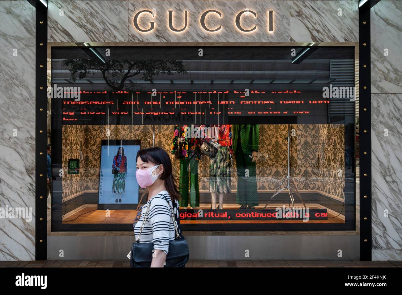A woman walks past the Italian luxury fashion brand Gucci logo and ...