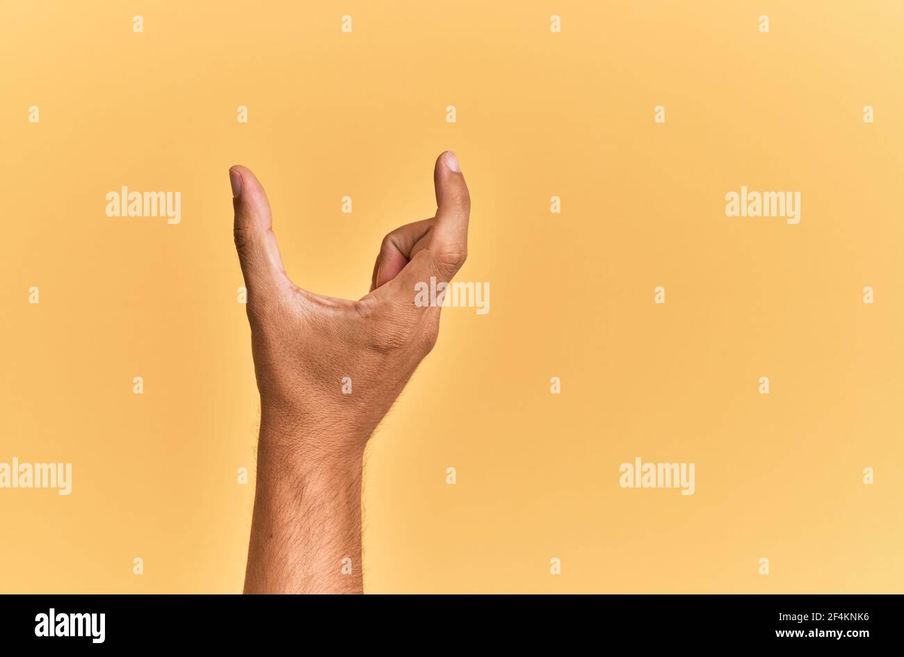 Arm and hand of caucasian man over yellow isolated background picking ...