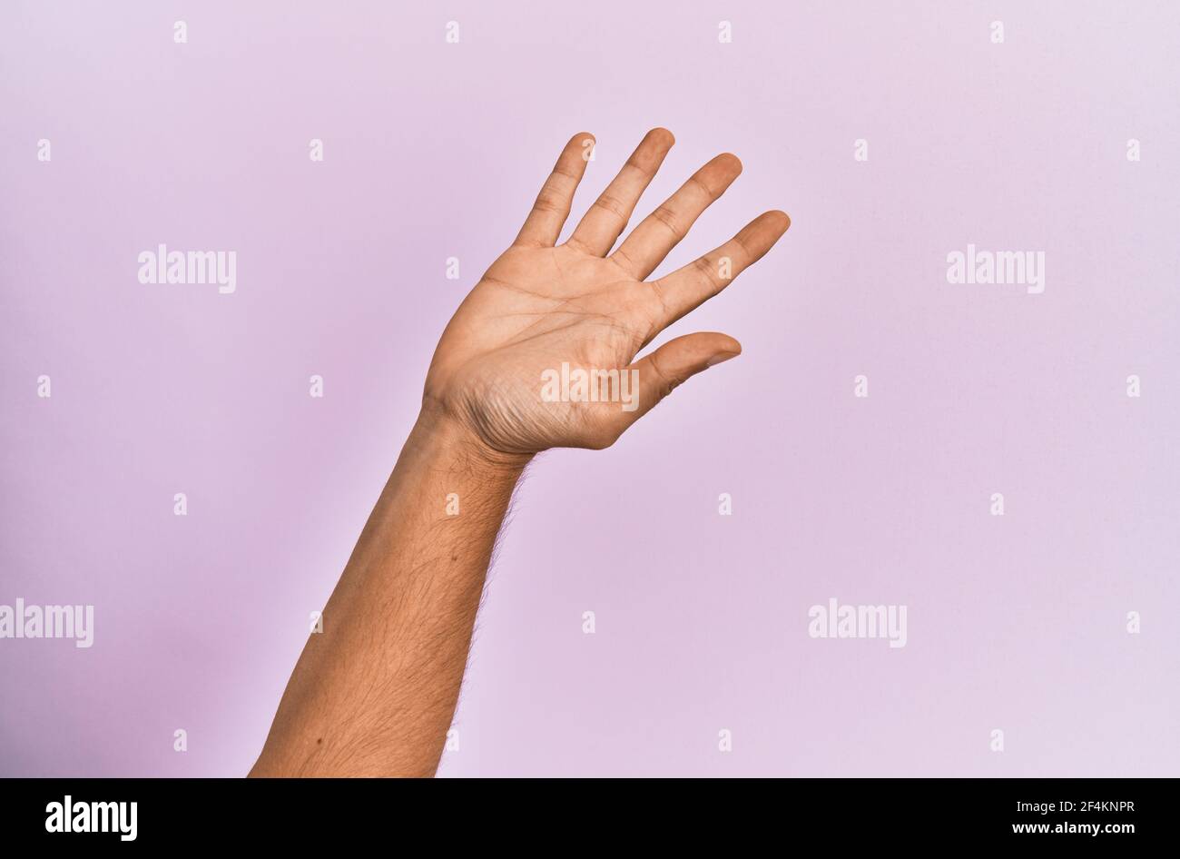 Arm and hand of caucasian young man over pink isolated background ...