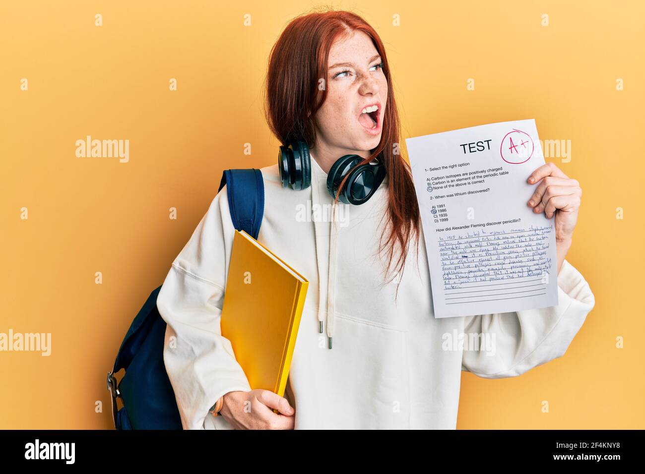 Young red head girl wearing student backpack holding passed test angry ...