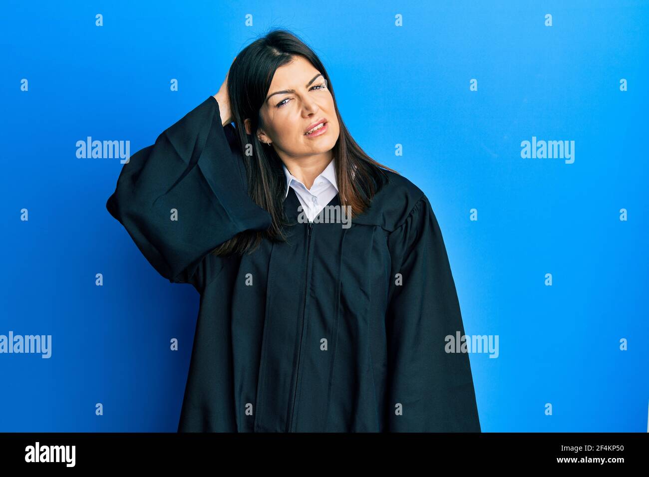 Young hispanic woman wearing judge uniform confuse and wonder about ...