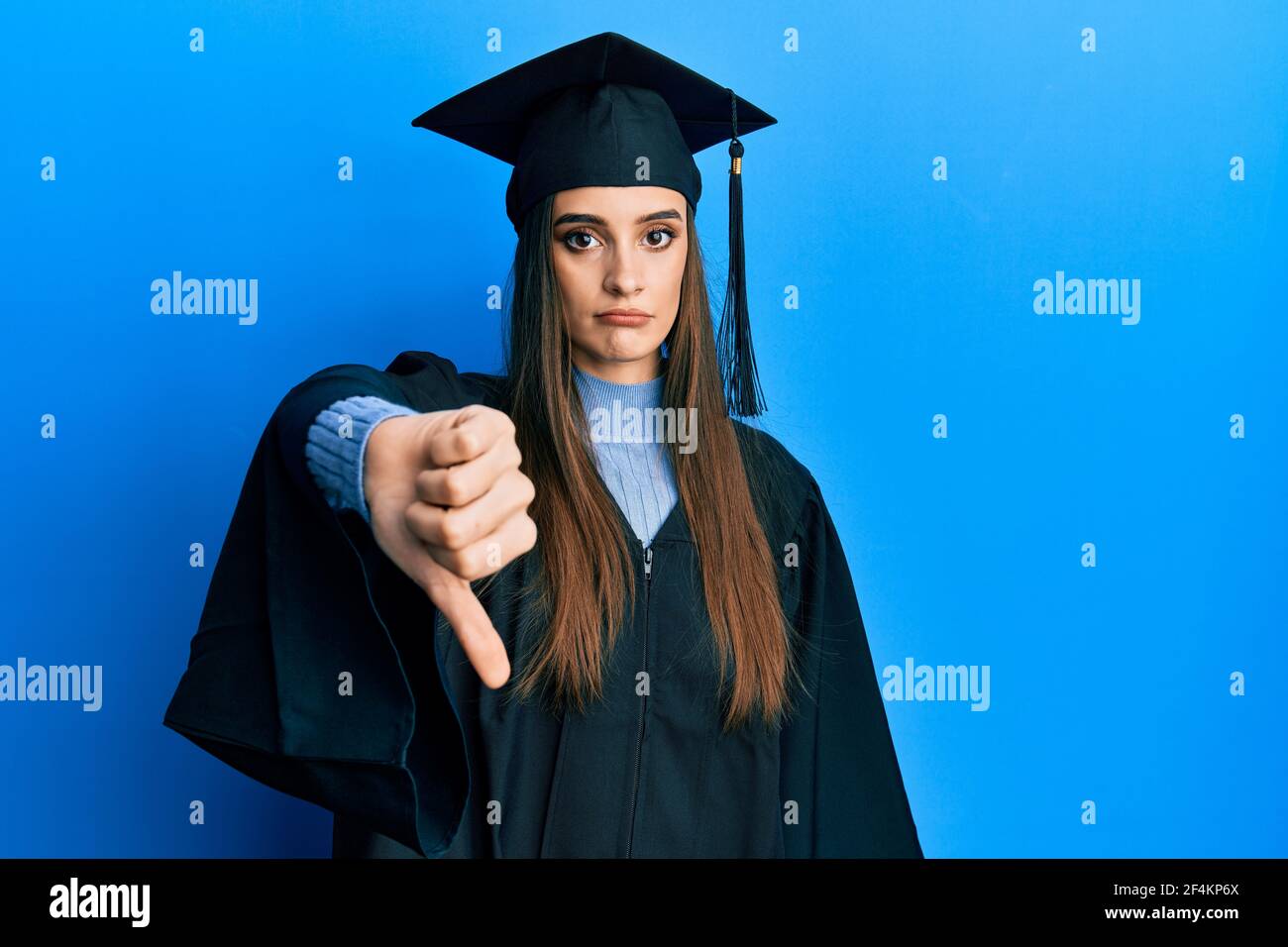 Beautiful brunette young woman wearing graduation cap and ceremony robe ...