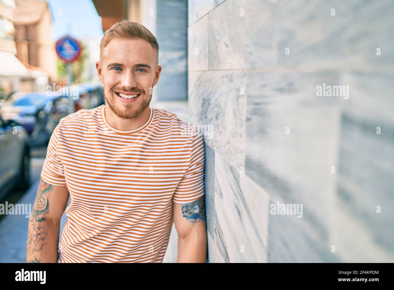 Young irish man smiling happy leaning on the wall at street of city ...