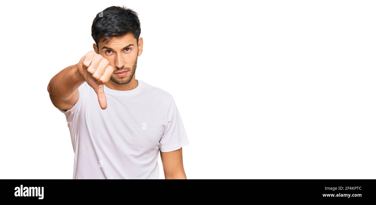 Young handsome man wearing casual white tshirt looking unhappy and ...
