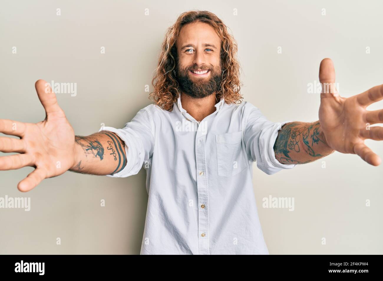 Handsome man with beard and long hair wearing casual white shirt ...