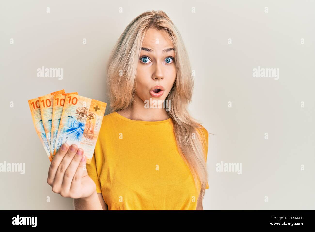 Beautiful caucasian blonde girl holding 10 swiss franc banknotes scared ...