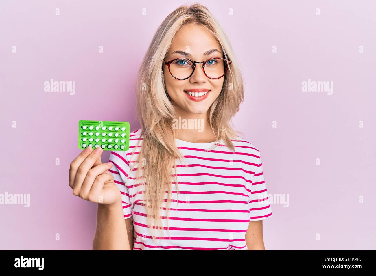 Beautiful caucasian blonde girl holding birth control pills looking ...