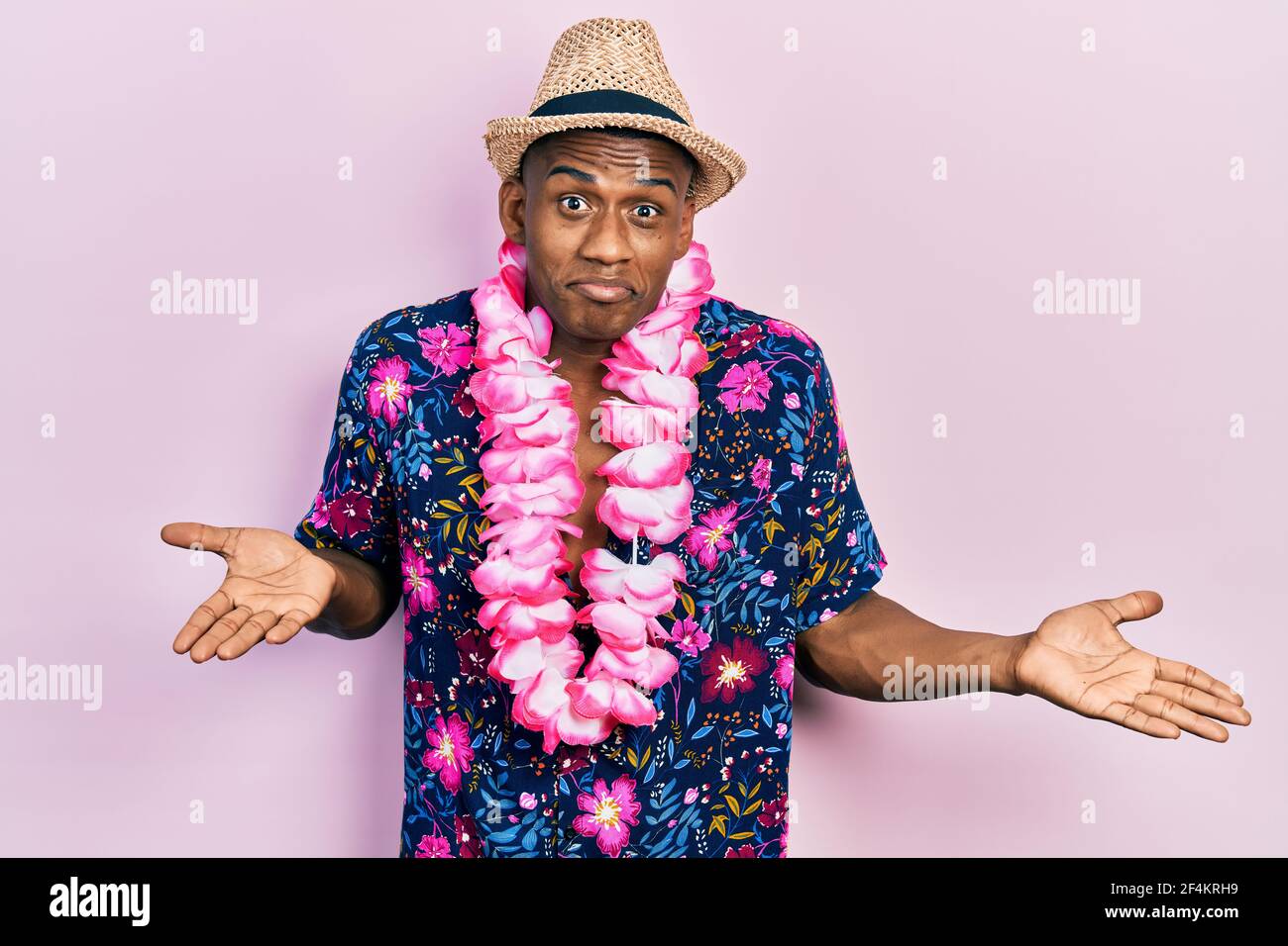 Young black man wearing summer shirt and hawaiian lei clueless and ...