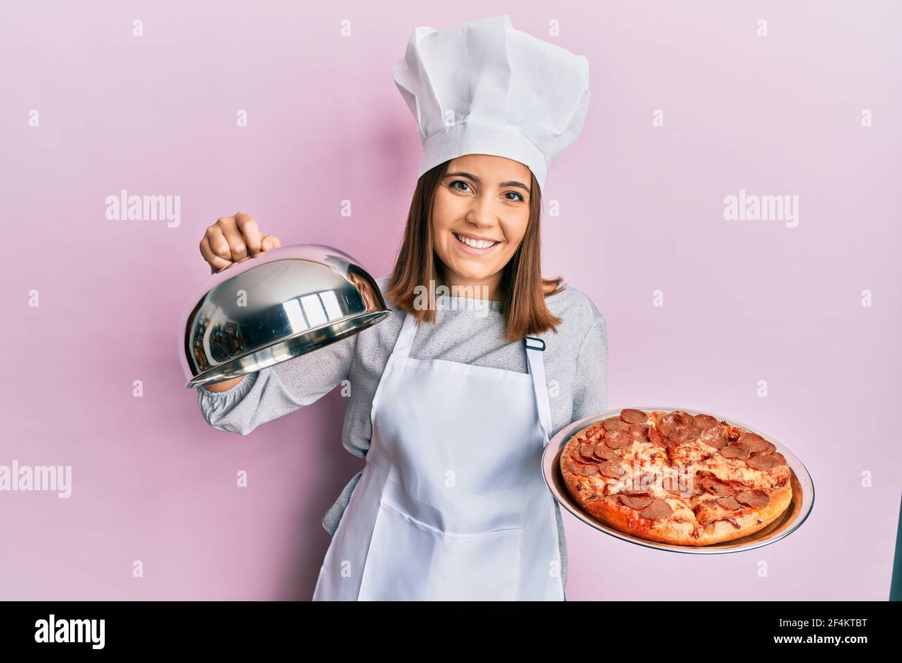 Young beautiful woman professional cook holding italian pizza smiling ...