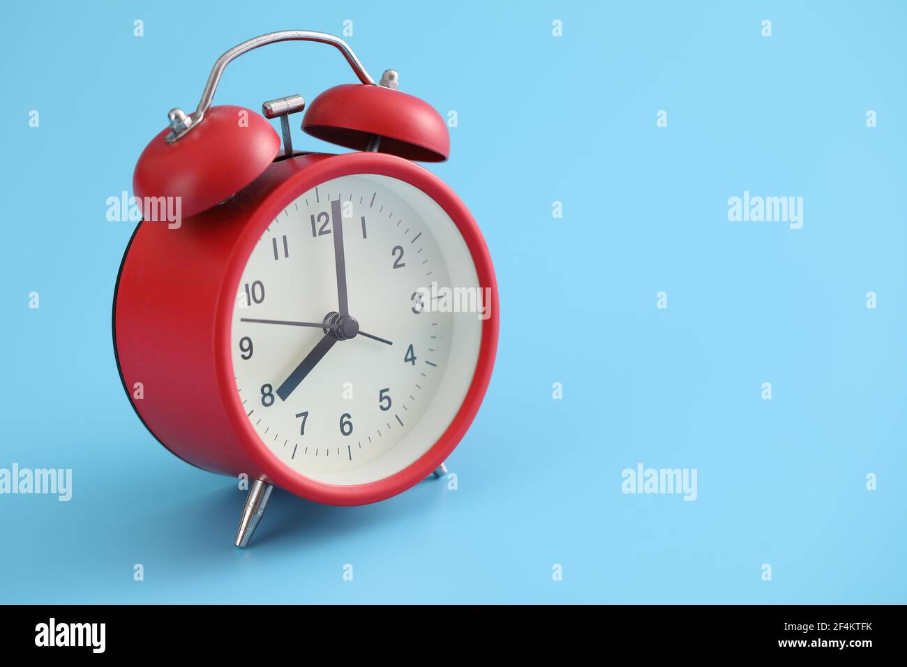 Red retro alarm clock isolated on a blue background Stock Photo - Alamy