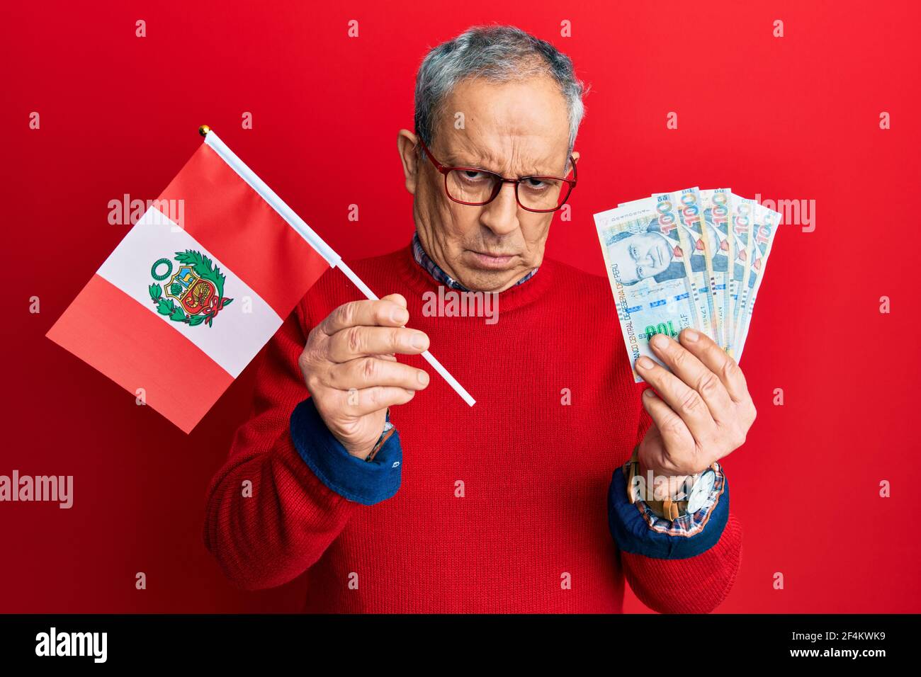 Handsome senior man with grey hair holding peru flag and peruvian sol ...