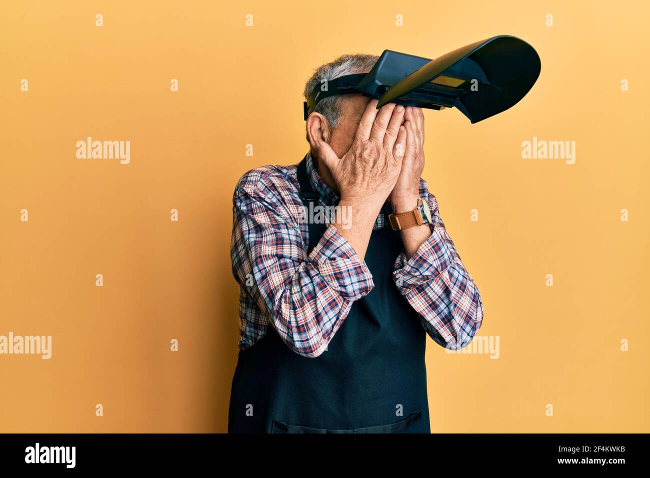 Handsome senior man with grey hair wearing welding protection mask with ...