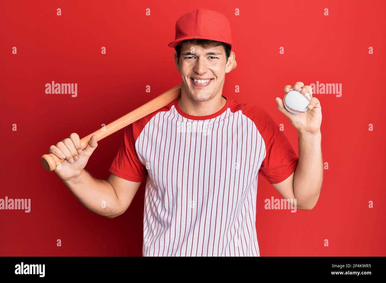 Handsome caucasian man playing baseball holding bat and ball looking ...
