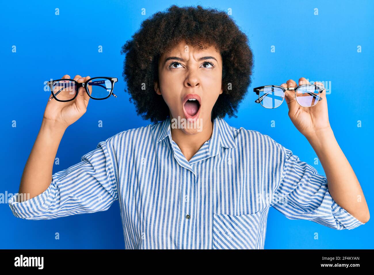 Young hispanic girl holding glasses angry and mad screaming frustrated ...
