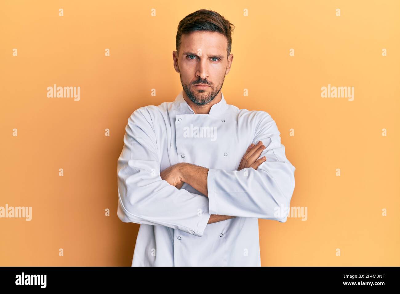 Handsome man with beard wearing professional cook uniform skeptic and ...
