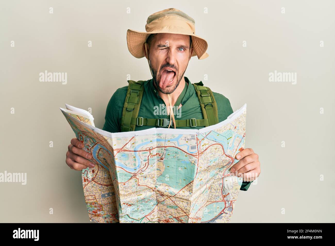 Handsome man with beard wearing explorer hat holding map sticking ...