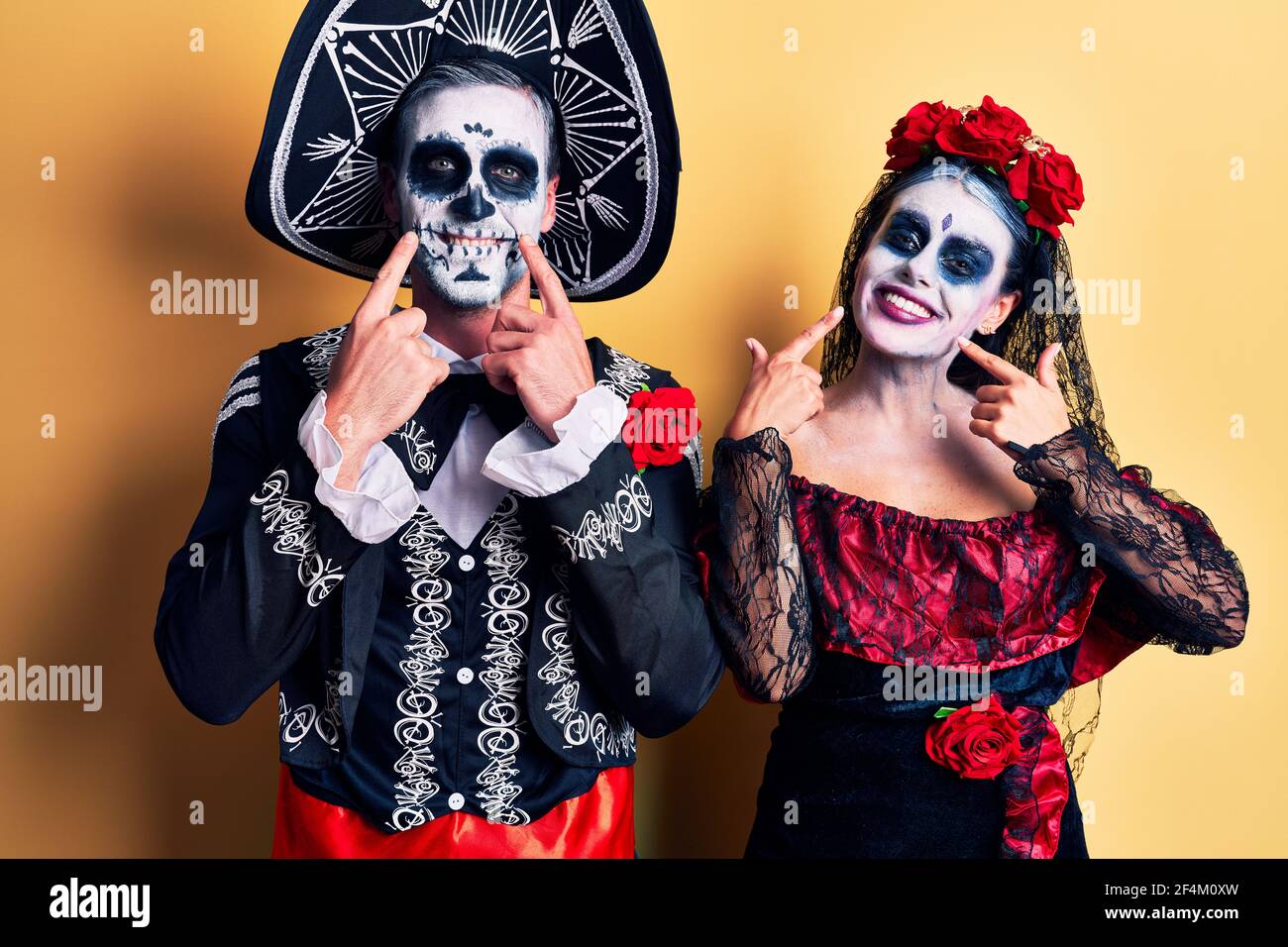 Young couple wearing mexican day of the dead costume over yellow ...