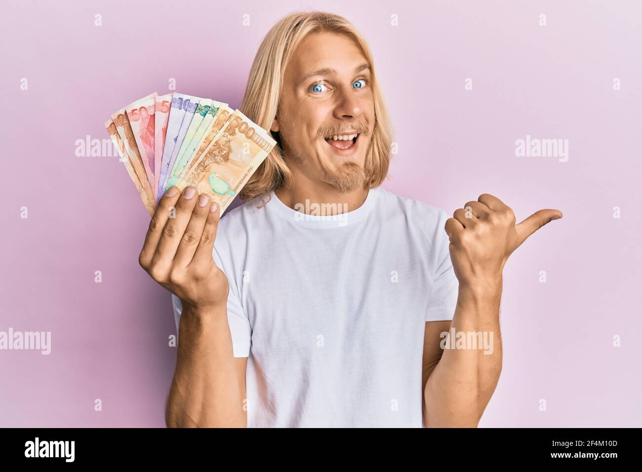 Caucasian young man with long hair holding philippine peso banknotes ...
