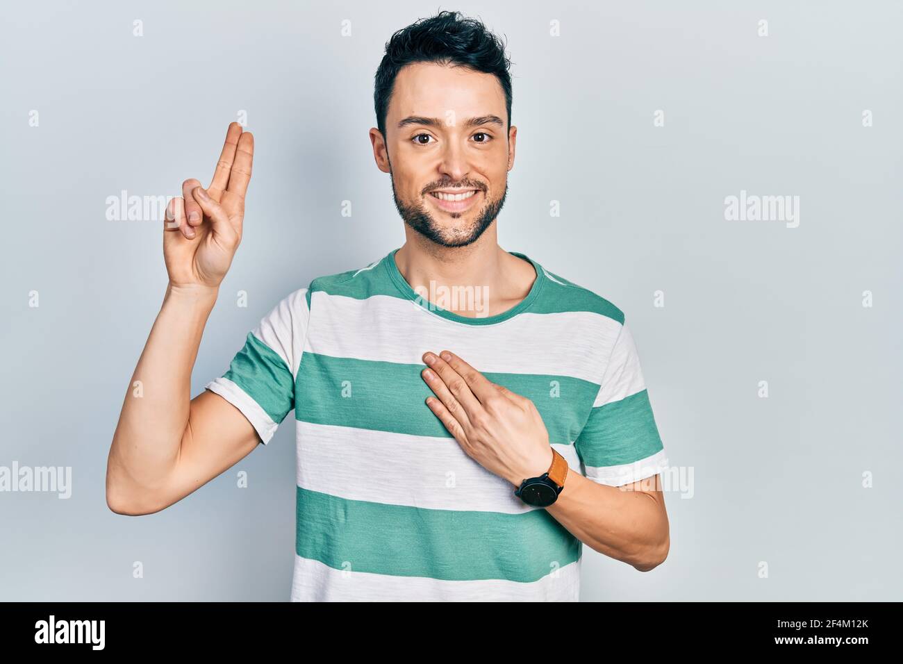 Young hispanic man wearing casual clothes smiling swearing with hand on ...