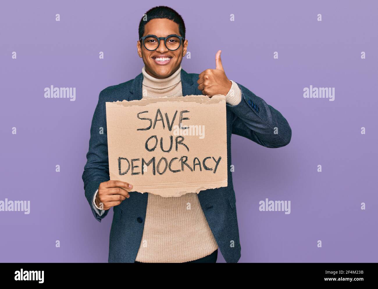 Young handsome hispanic man holding save our democracy protest banner ...