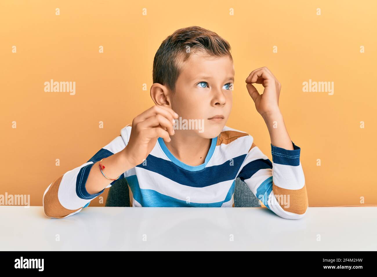 Adorable caucasian kid wearing casual clothes sitting on the table ...