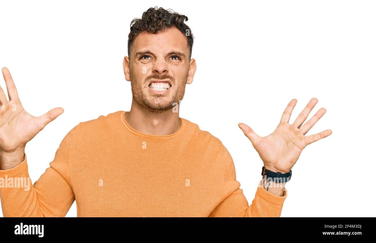 Young hispanic man wearing casual clothes crazy and mad shouting and ...