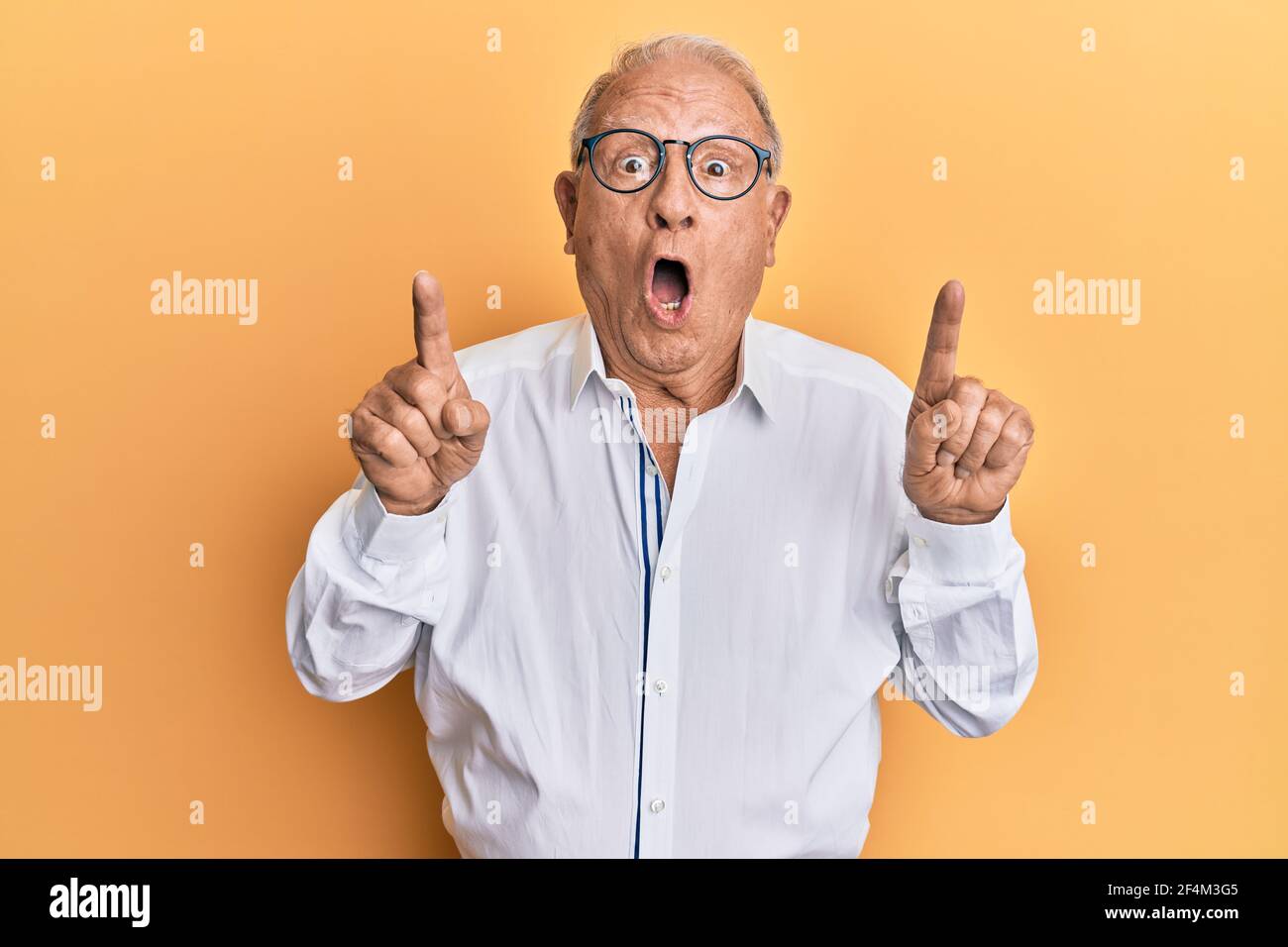 Senior caucasian man pointing up with fingers afraid and shocked with ...
