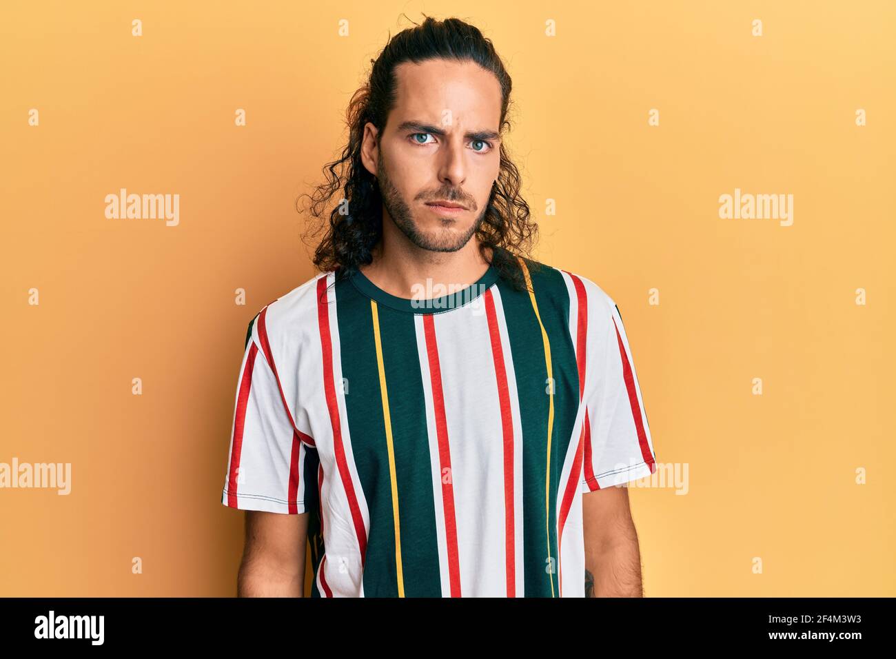 Young handsome man with long hair wearing casual clothes skeptic and ...