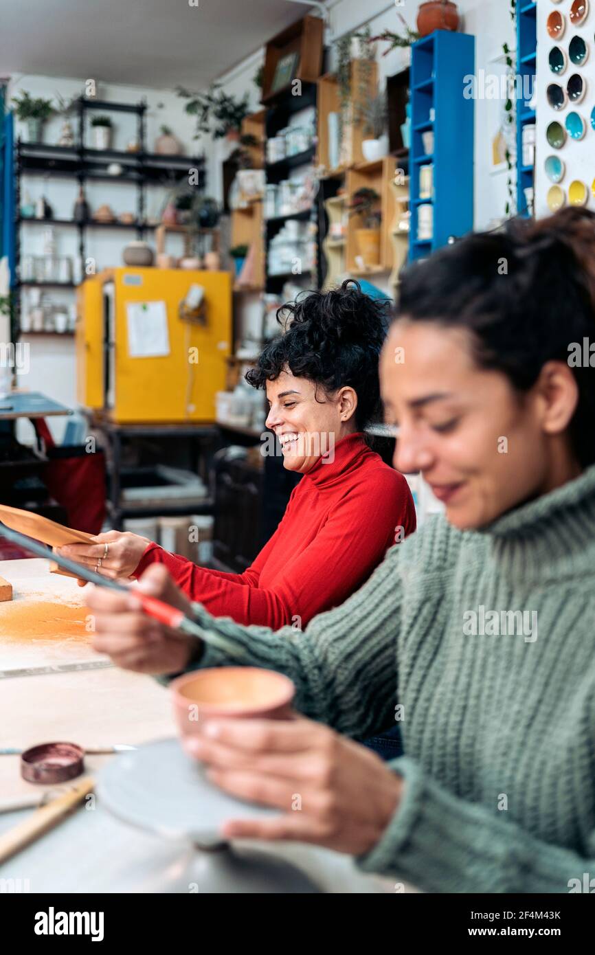 Stock photo of two happy women painting ceramic pieces during pottery ...