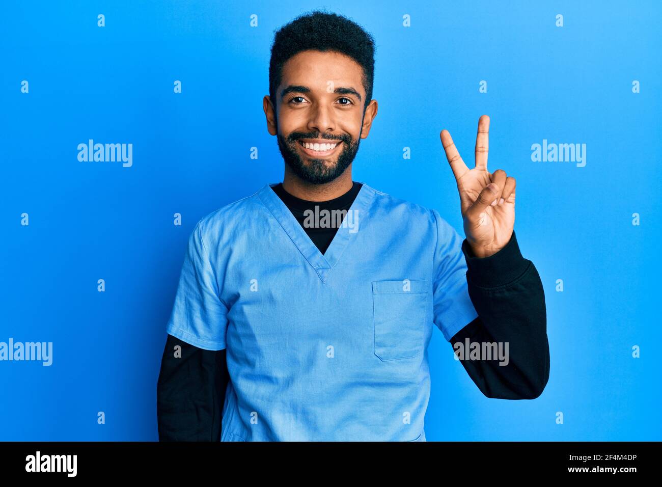 Handsome hispanic man with beard wearing blue male nurse uniform ...