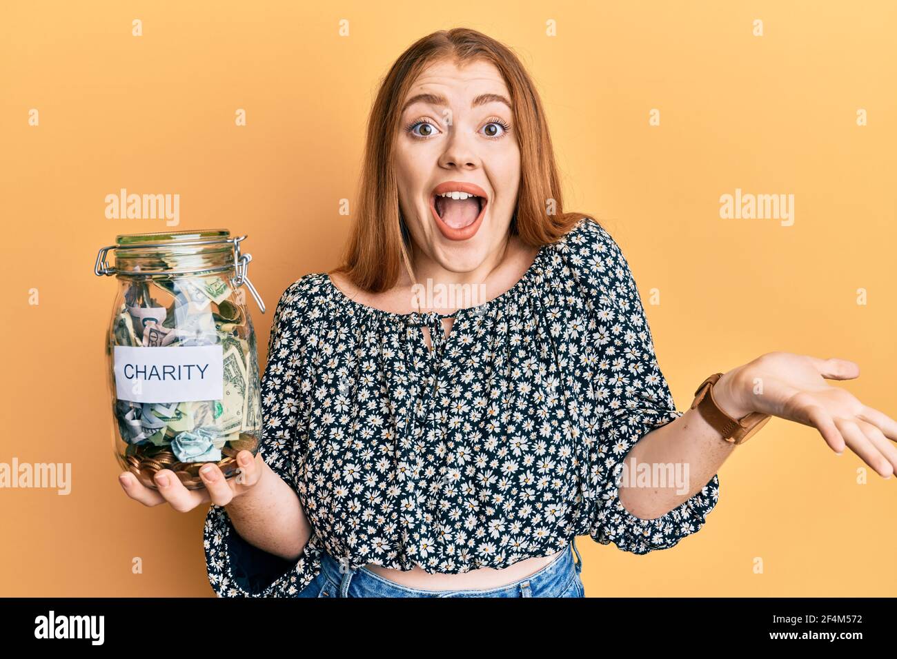 Young beautiful redhead woman holding charity jar with money ...