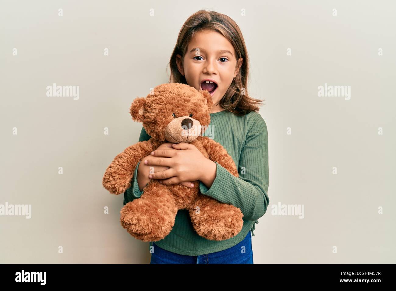 Little beautiful girl hugging teddy bear celebrating crazy and amazed ...