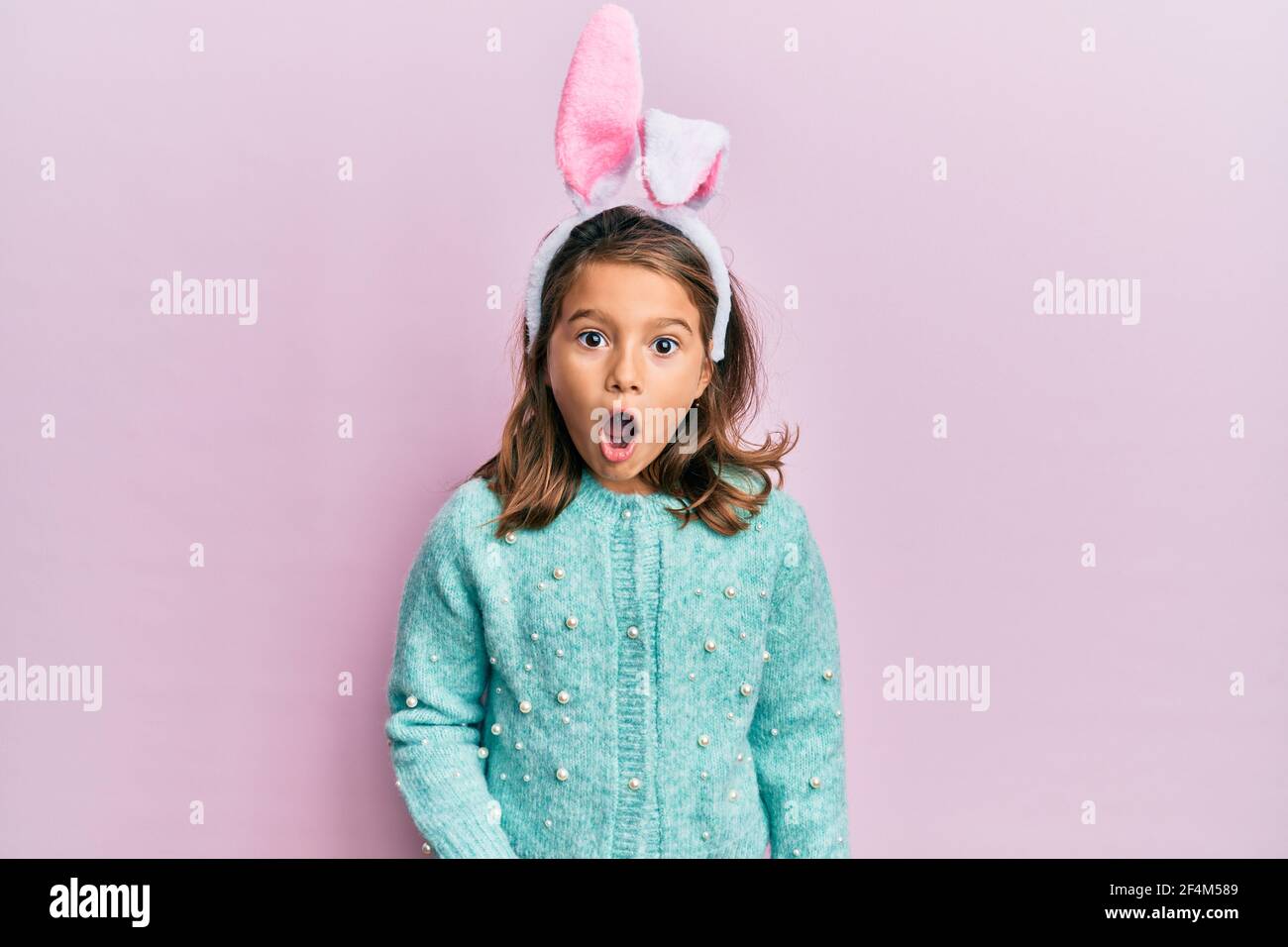 Little beautiful girl wearing cute easter bunny ears afraid and shocked ...