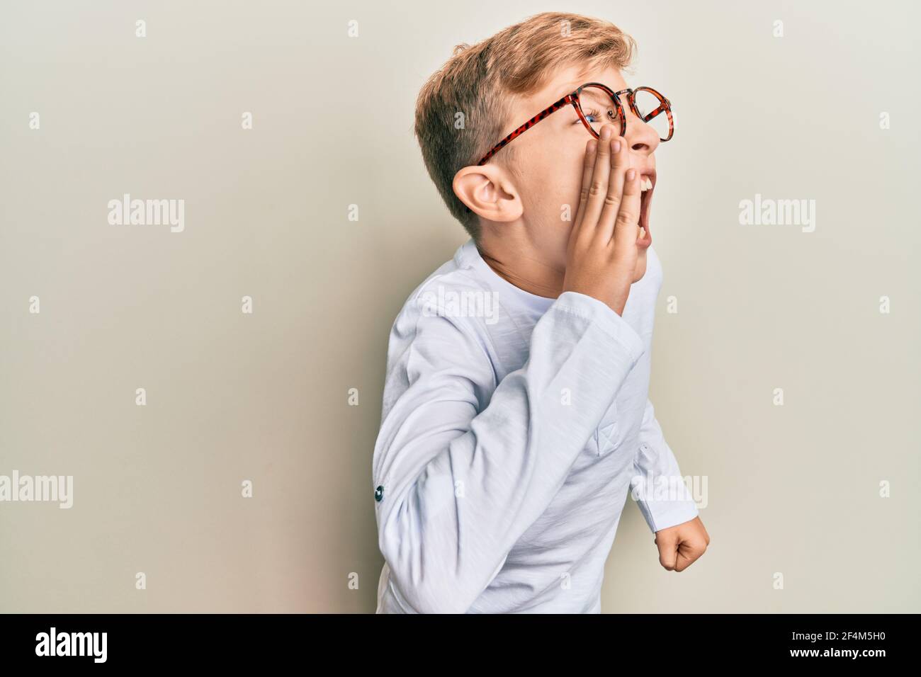 Little caucasian boy kid wearing casual clothes and glasses shouting ...
