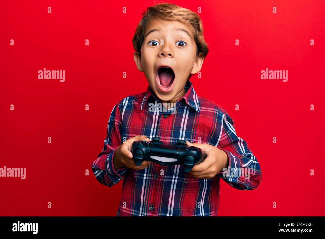 Adorable latin kid playing video game holding controller afraid and ...