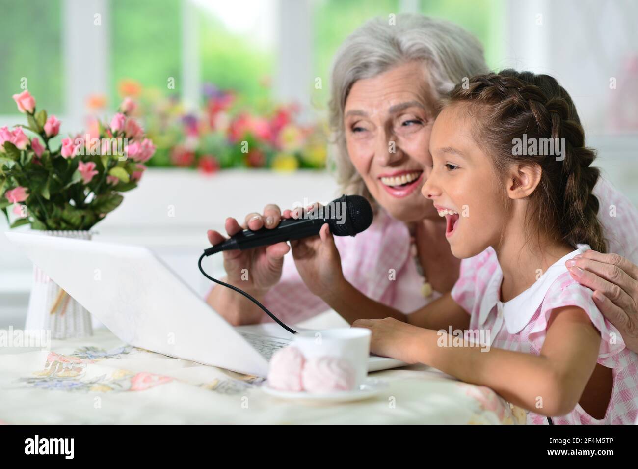 Portrait of grandmother and granddaughter singing karaoke Stock Photo ...