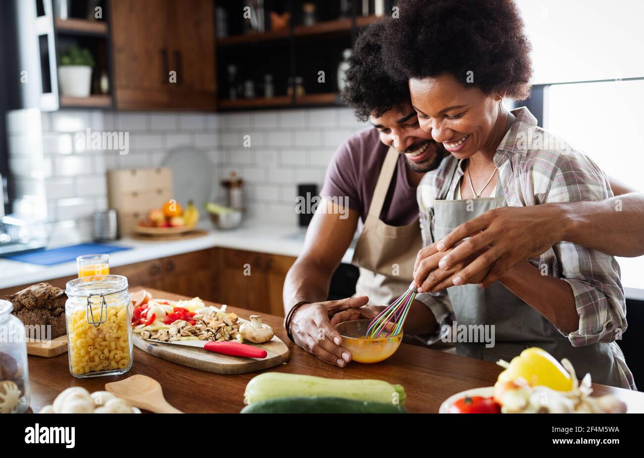 Beautiful young couple having fun and laughing while cooking in kitchen ...