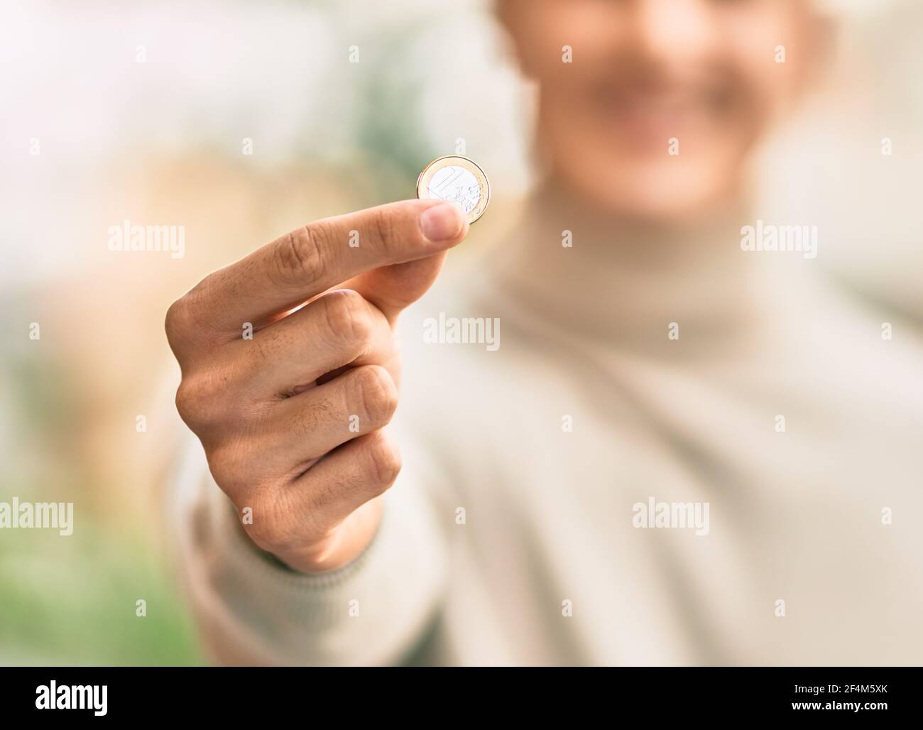 Young hispanic man smiling happy holding 1 euro coin at the city Stock ...