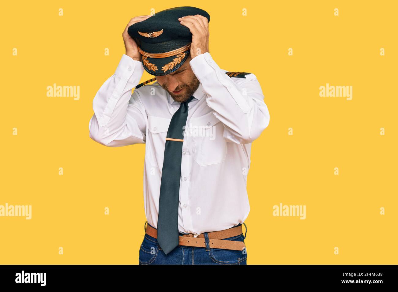 Handsome man with beard wearing airplane pilot uniform suffering from ...