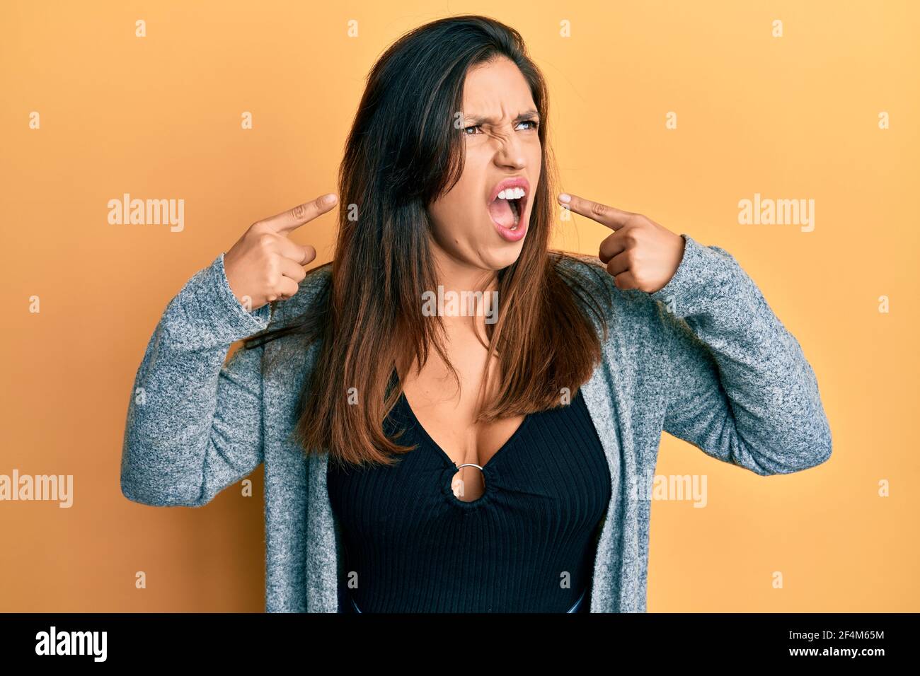 Beautiful hispanic woman pointing to mouth with fingers angry and mad ...