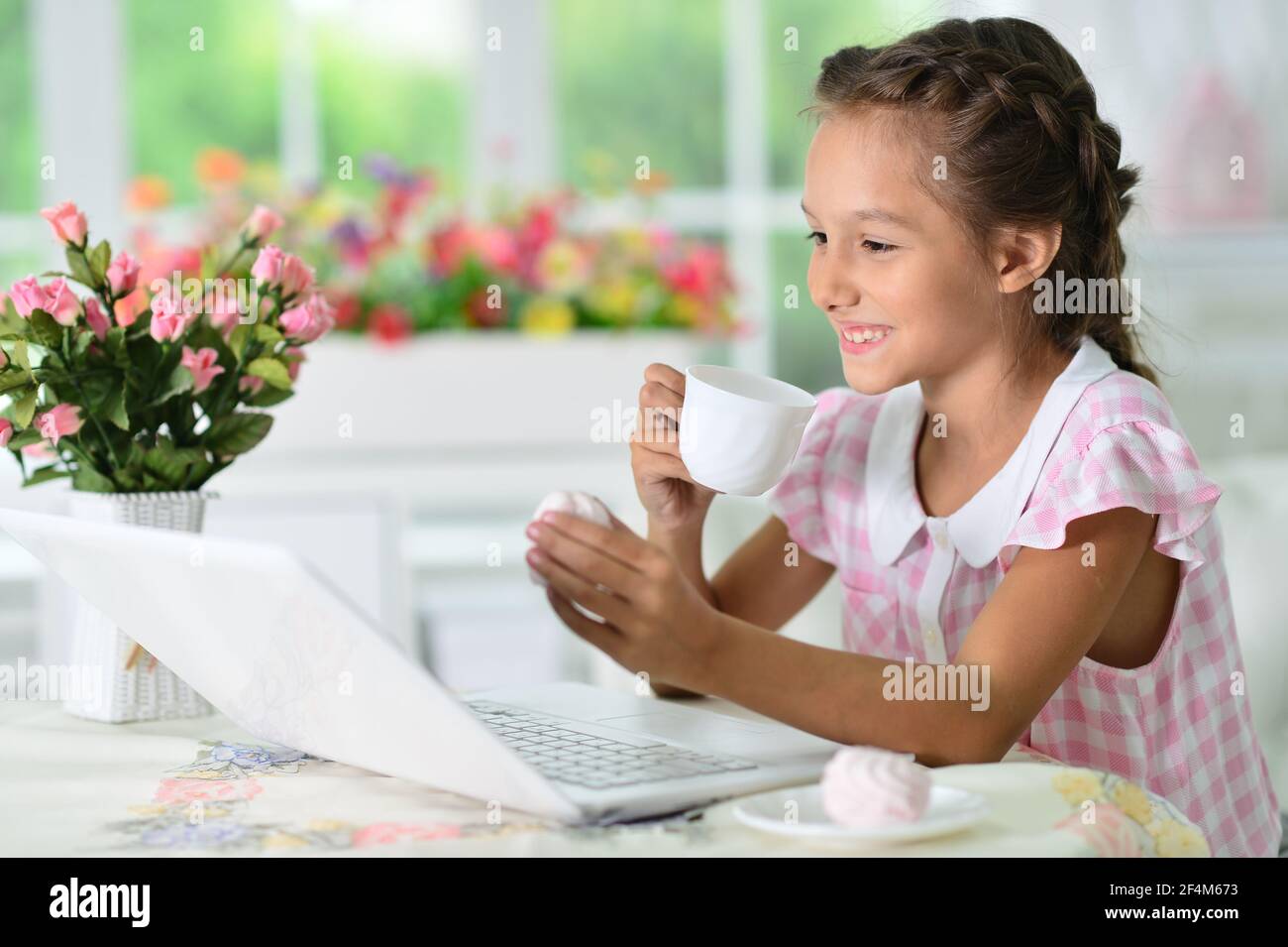 Emotional cute girl using laptop and drinking tea Stock Photo - Alamy