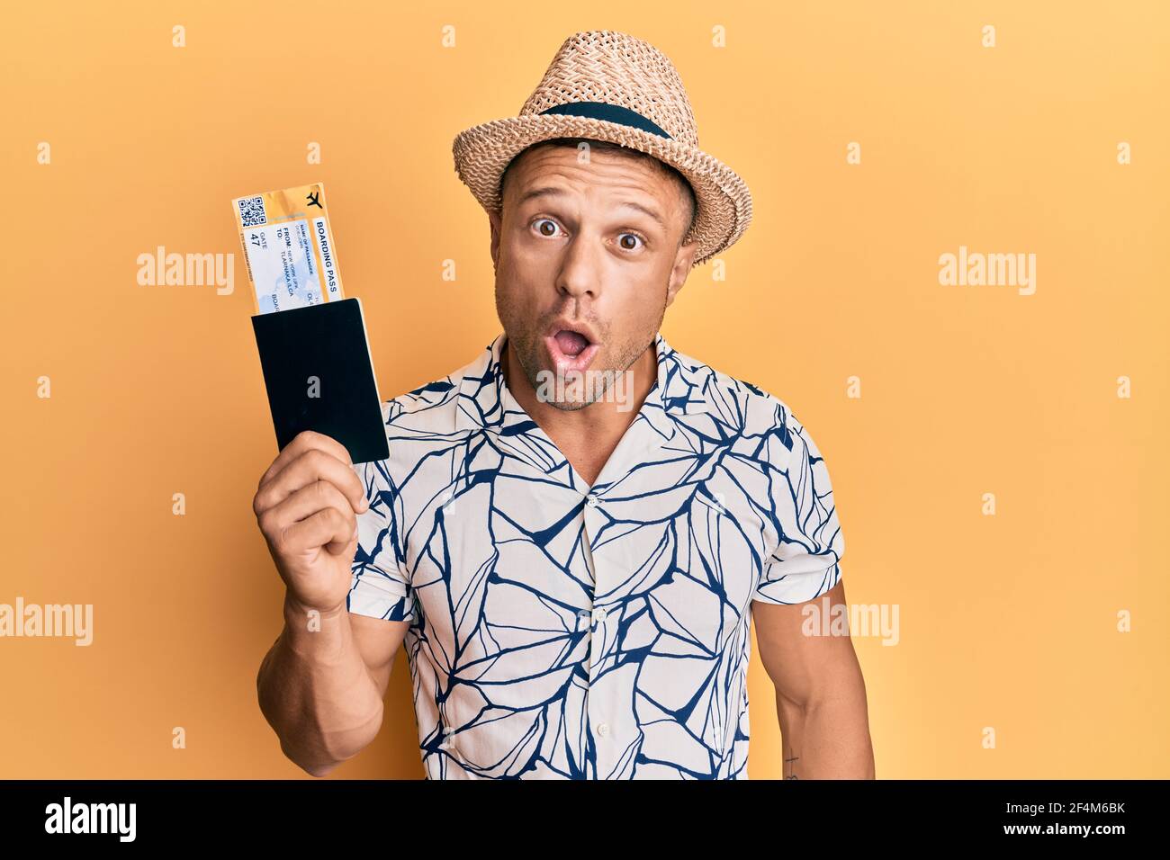 Handsome muscle man holding boarding pass and passport scared and ...