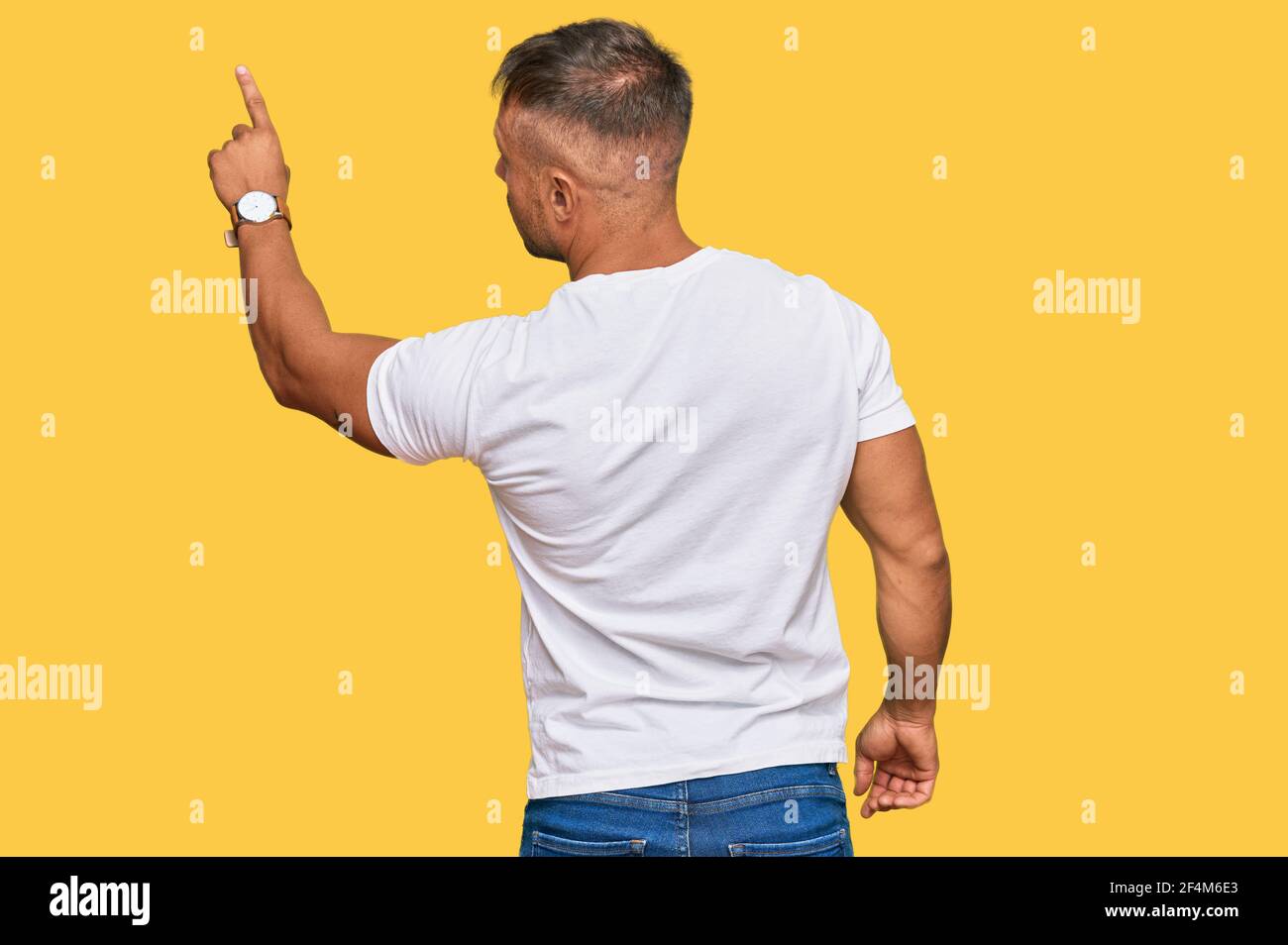 Handsome muscle man wearing casual white tshirt posing backwards ...