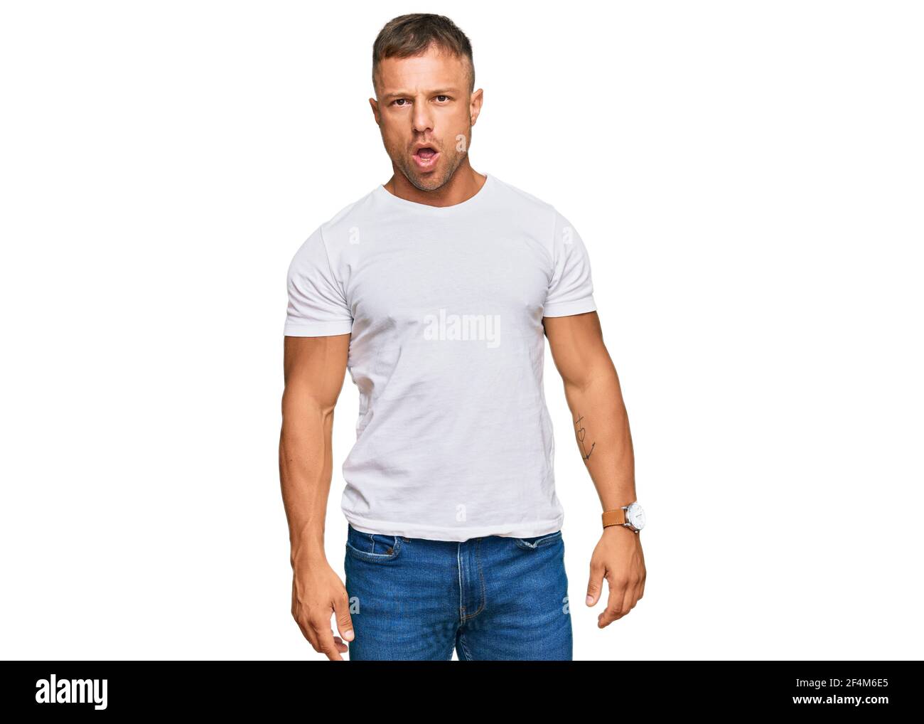 Handsome muscle man wearing casual white tshirt in shock face, looking ...