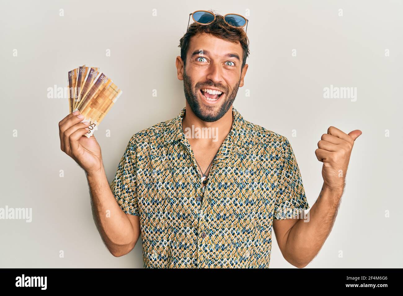 Handsome man with beard holding 500 norwegian krone banknotes pointing ...